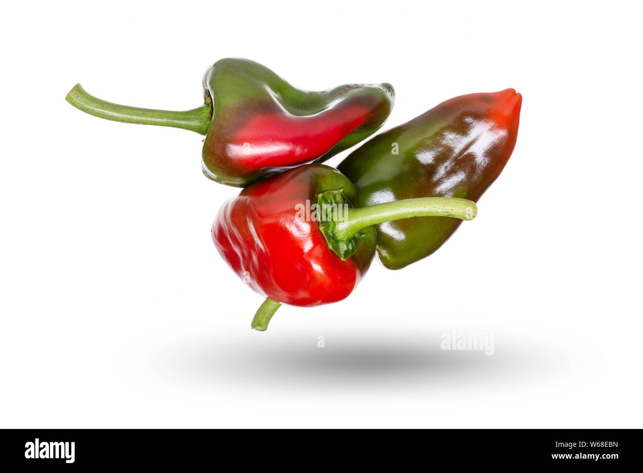 Group of fresh red and green pepper flying on white background ...
