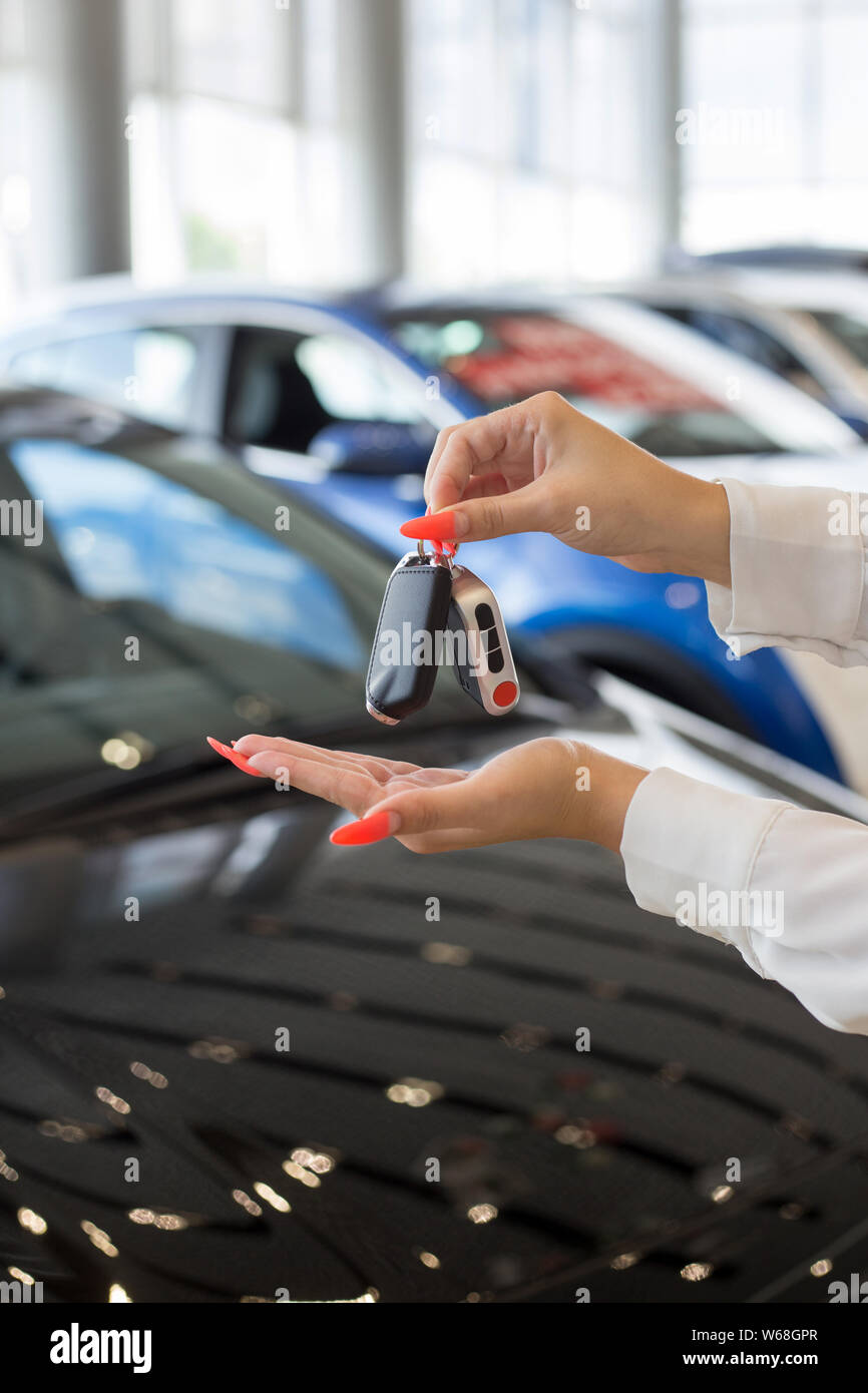 Dealer woman holding keys to a new car. Car auto dealership. Modern and ...