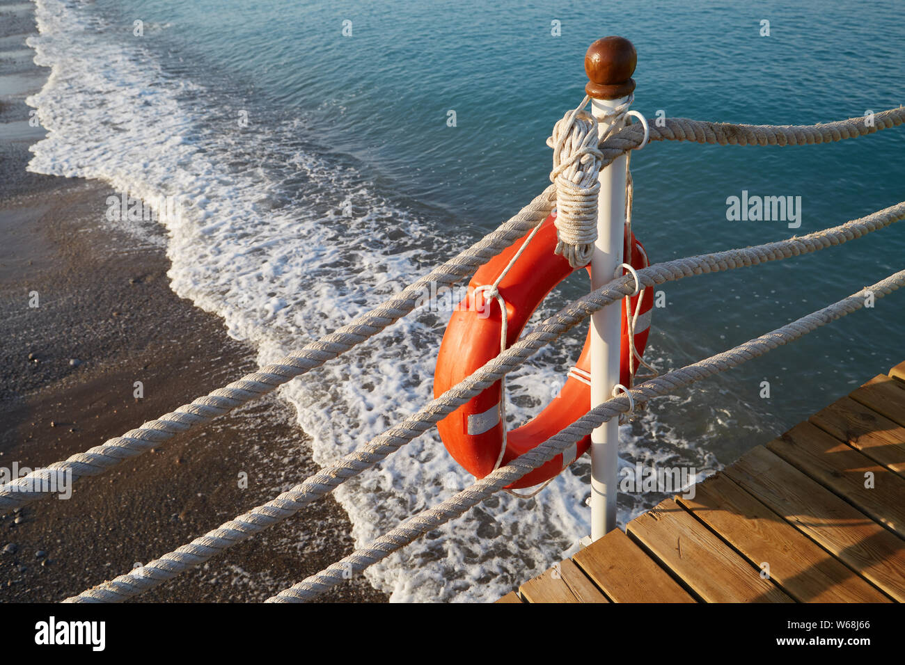 Lifebuoy with a rope is at the edge of water on the beach Stock Photo ...