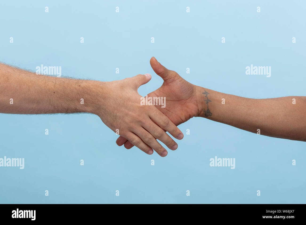 Closeup shot of human holding hands isolated on blue studio background ...