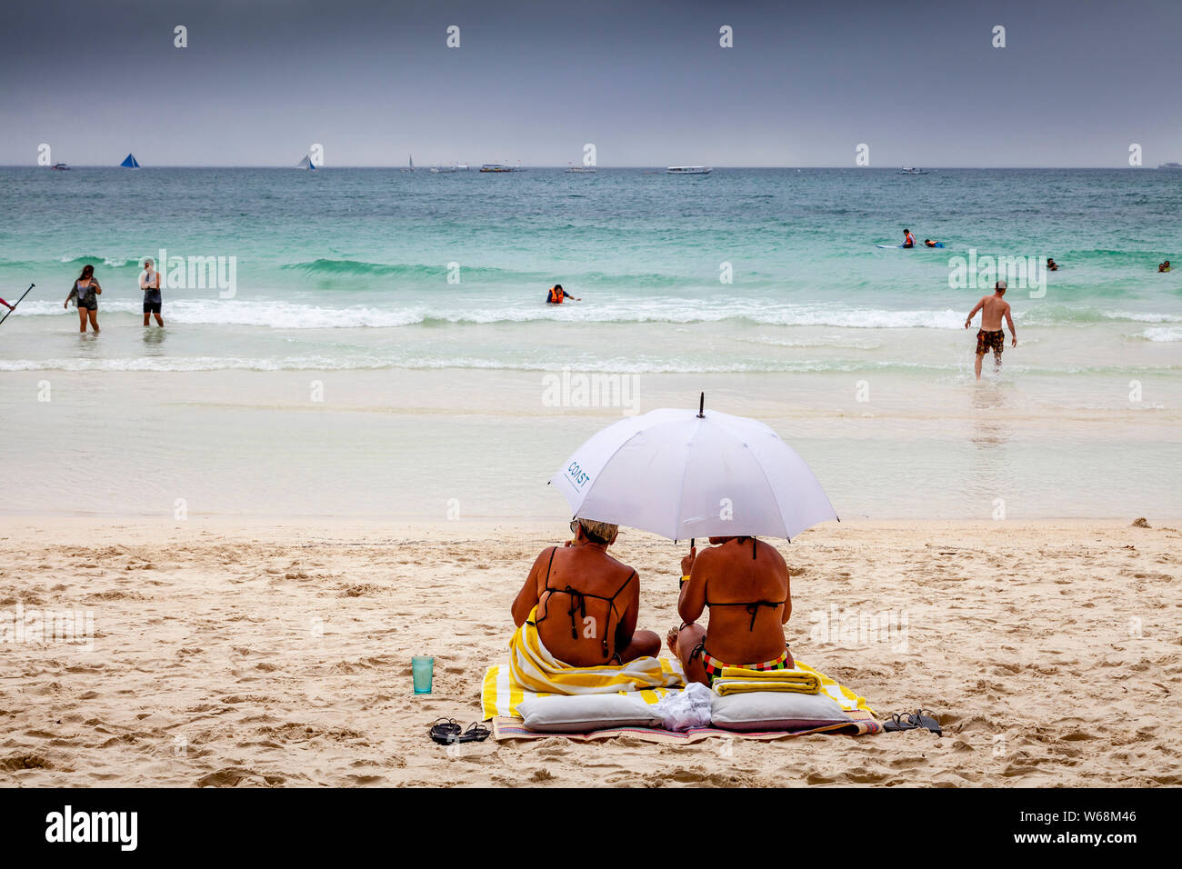 Two Women Sit Under An Umbrella, White Beach, Boracay, Aklan, The ...