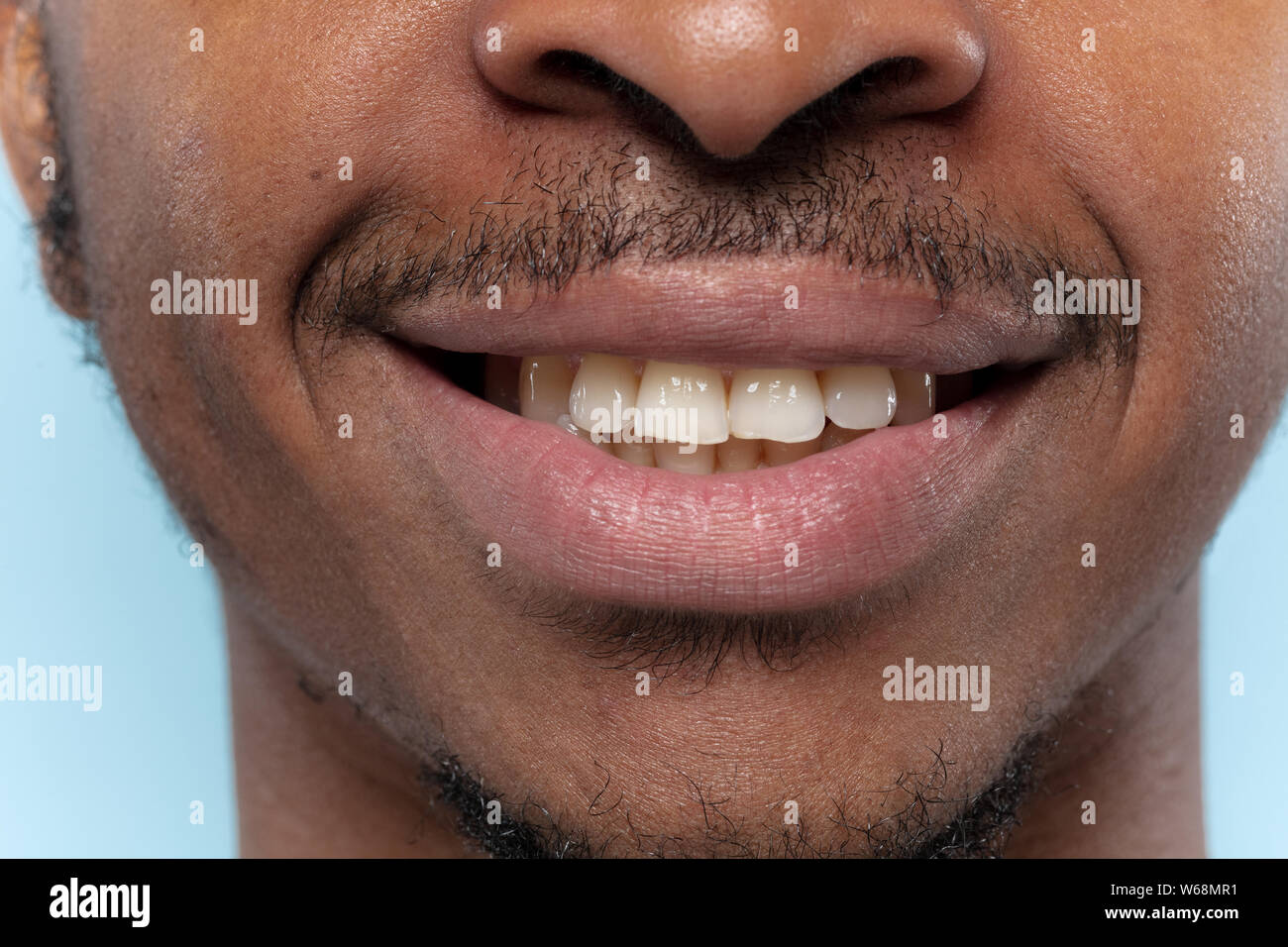 Close up portrait of young african-american man on blue background ...