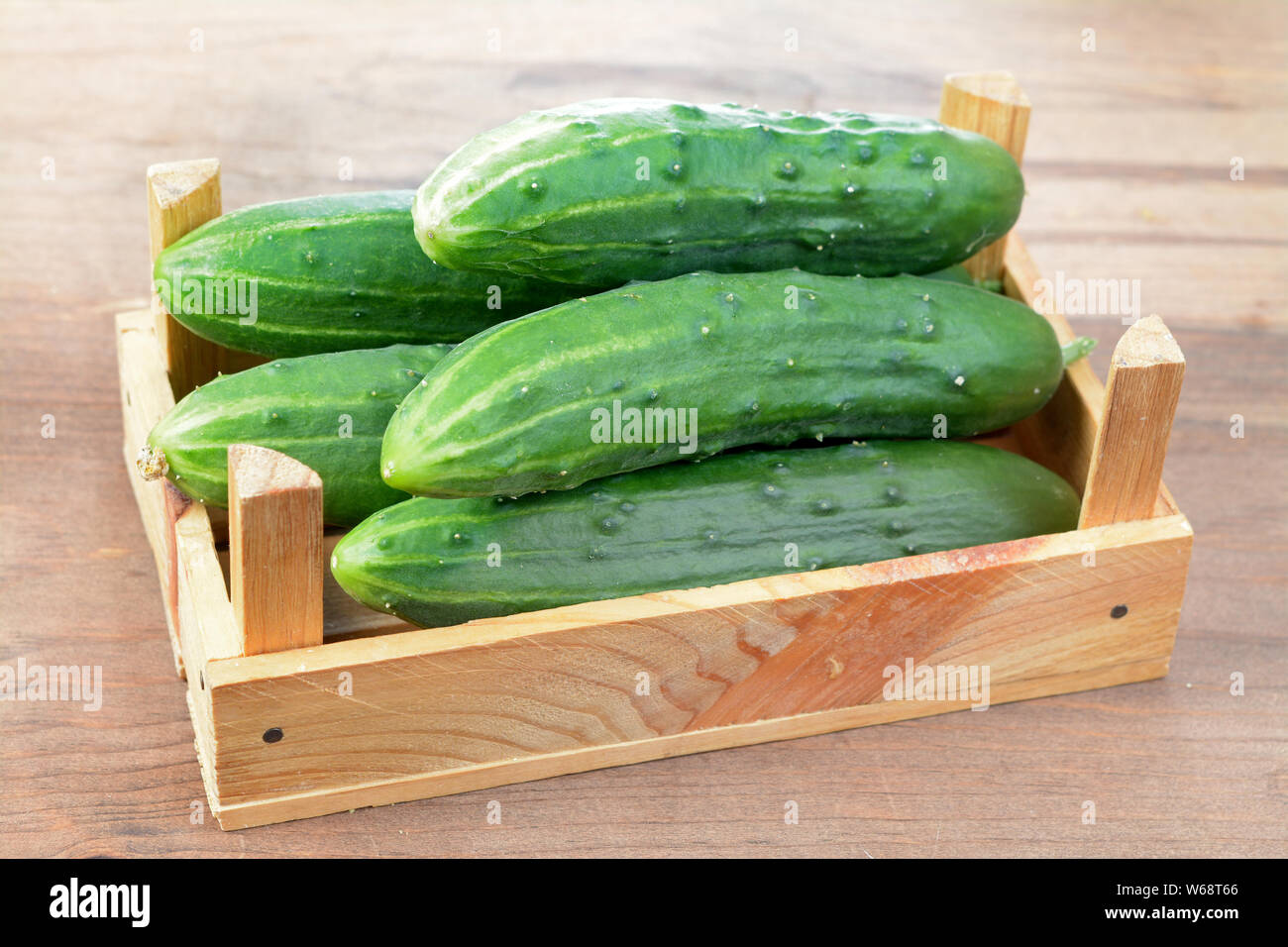 a group organic cucumbers in wooden crate on rustic table Stock Photo ...