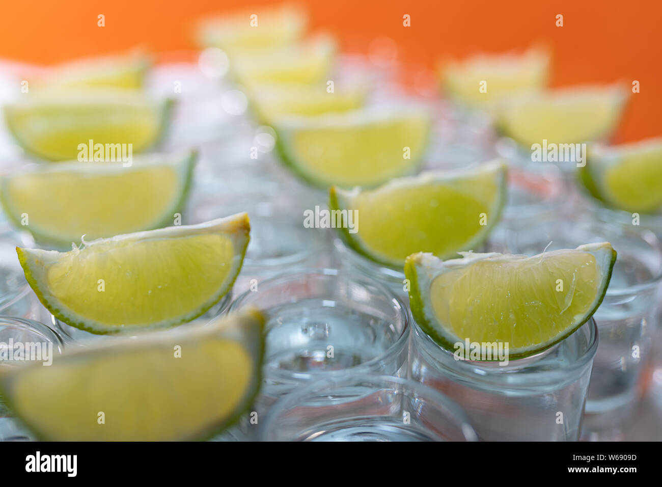 Detail of lime green slices on top of tequila shots with an orange ...
