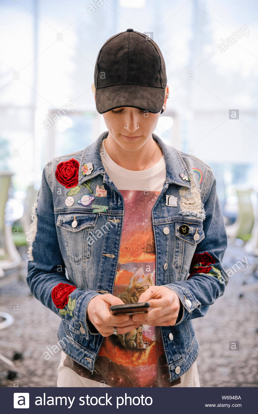 Student wearing cap and denim jacket using smartphone Stock Photo - Alamy