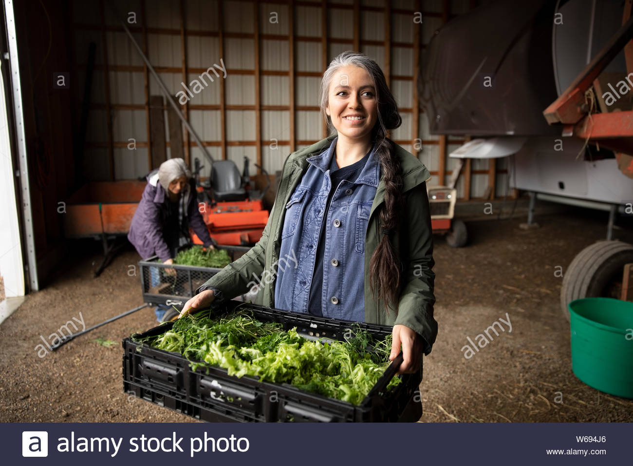 Portrait smiling female farmer with harvested vegetables in barn Stock ... Portrait smiling female farmer with harvested vegetables in barn Stock ...