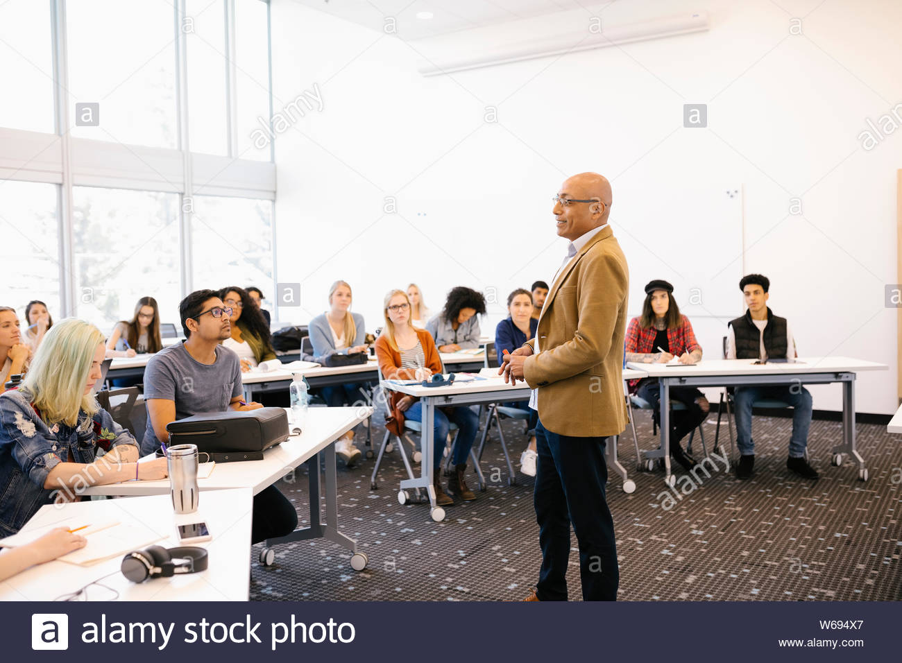 Univeristy lecturer explaining to students in classroom Stock Photo - Alamy