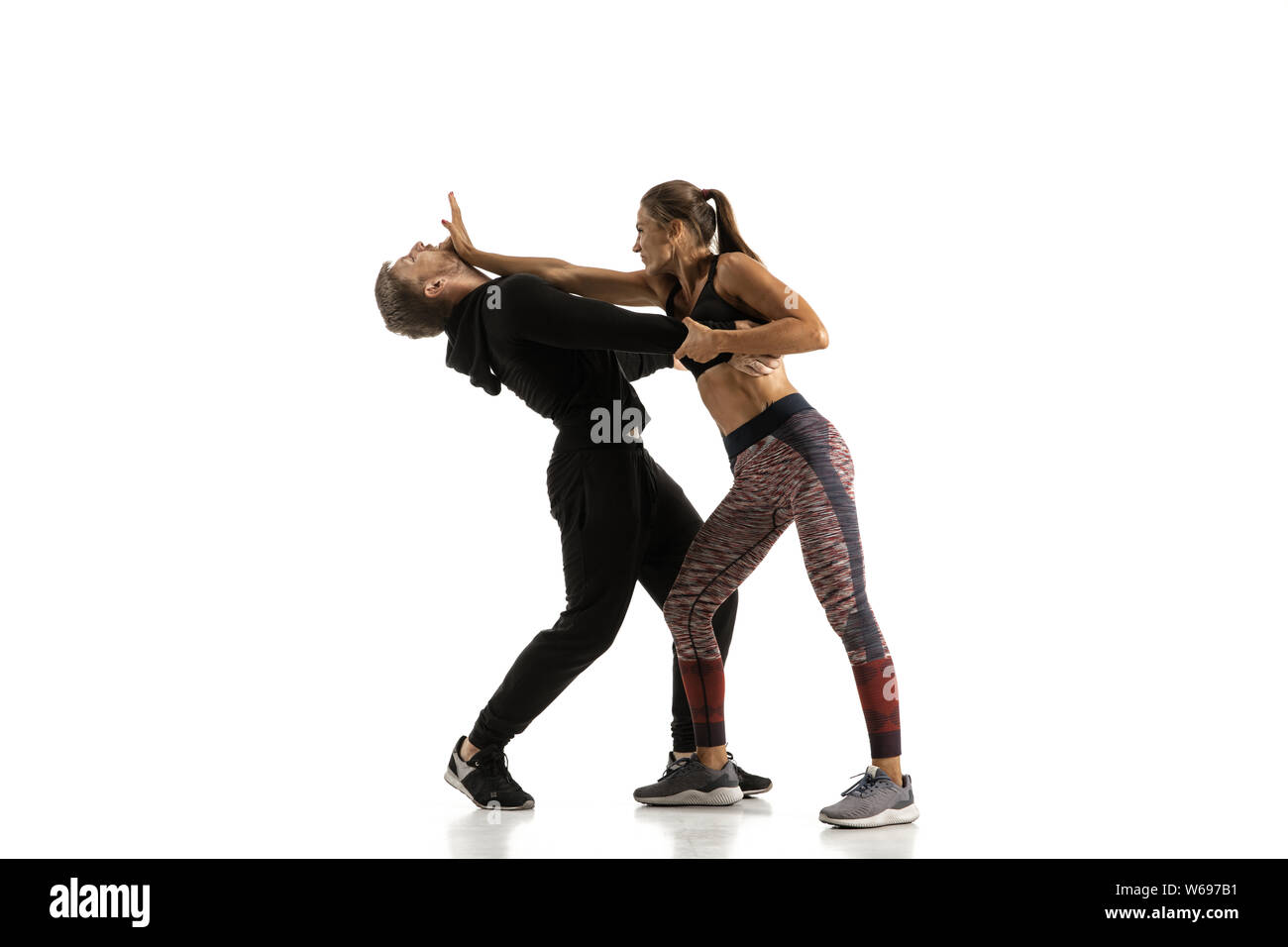 Man in black outfit and athletic caucasian woman fighting on white ...