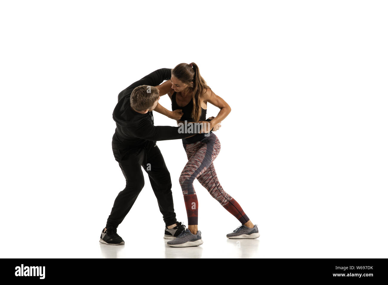 Man in black outfit and athletic caucasian woman fighting on white ...