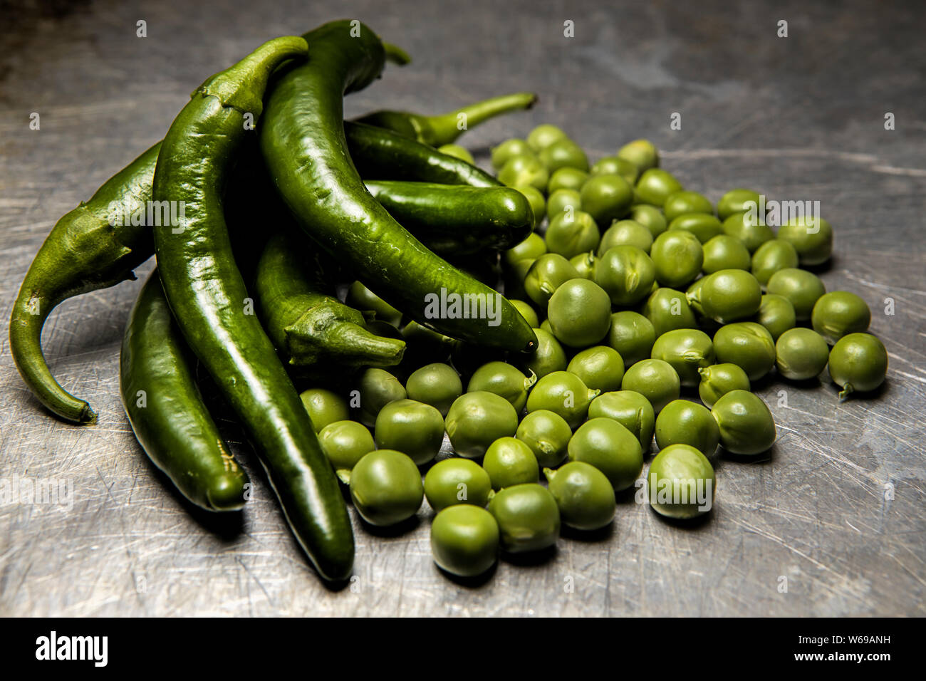 A studio photo of a group of green peas and green chili peppers Stock ...