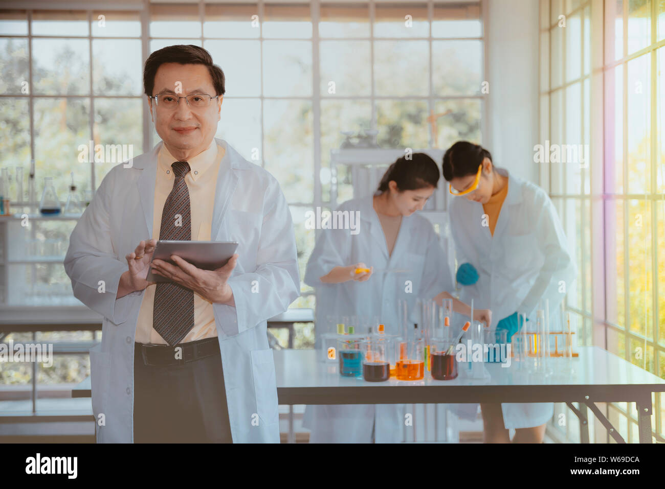 Professor holding laptop with trainee testing chemistry in lab on ...