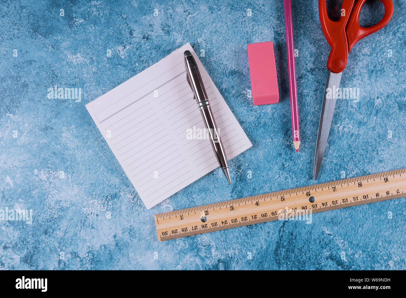 Assortment of school supplies. Ruler, scissors, notepad, rubber on blue ...