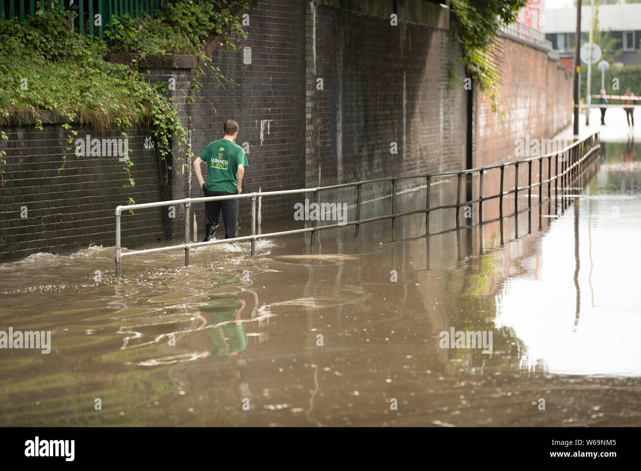 Stockport, UK, 31 Jul 2019. A person wades through the water in the dip ...