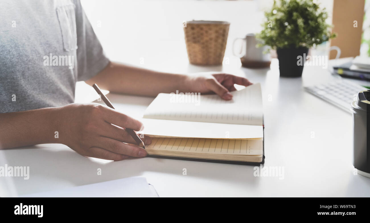 Close-up of man writing his idea concepts on notebook in comfortable ...