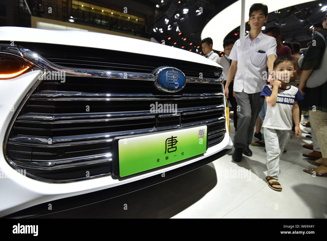 --FILE--Visitors walk past a Tang plug-in hybrid SUV of BYD displayed ...