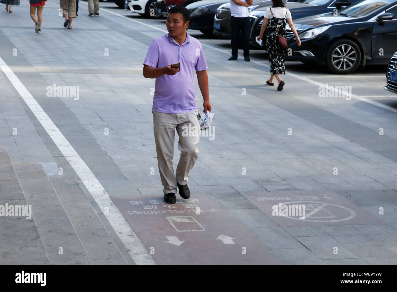 A pedestrian uses his smartphone as he walks on the mobile phone ...