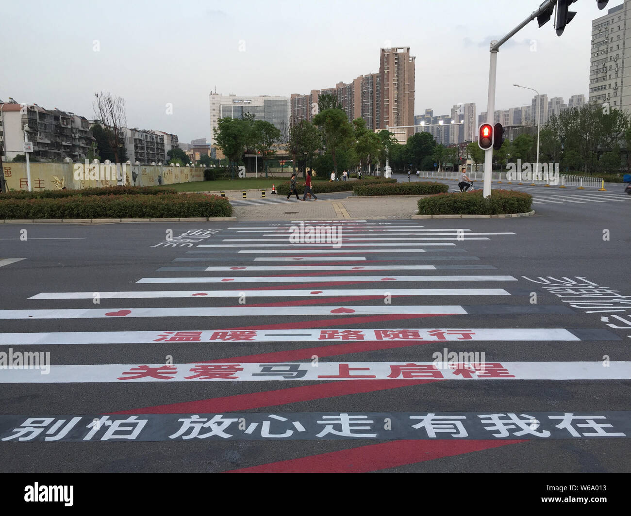 Pedestrians walk on a zebra crossing with some sweet slogans on road ...