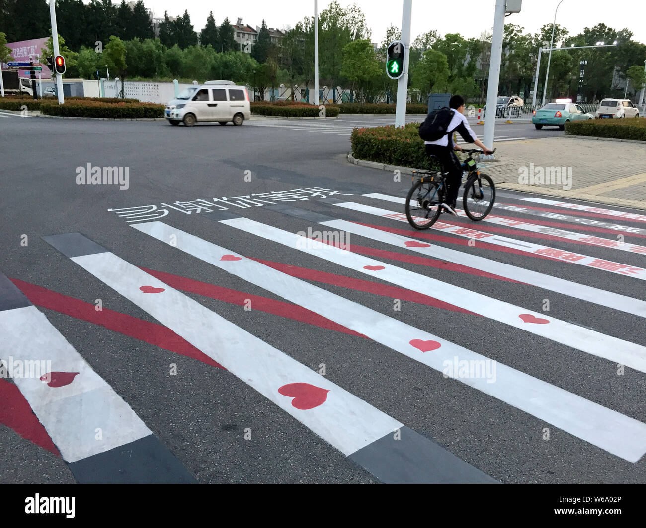 A cyclist rides past a zebra crossing with some sweet slogans on road ...