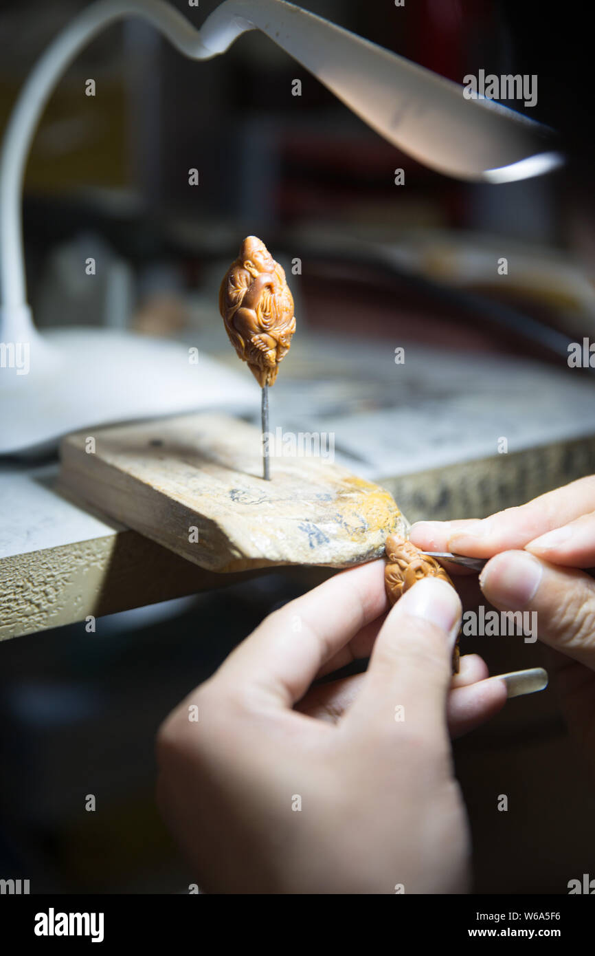 An apprentice creates a fruit pit carving at a studio in Zhoushan ...