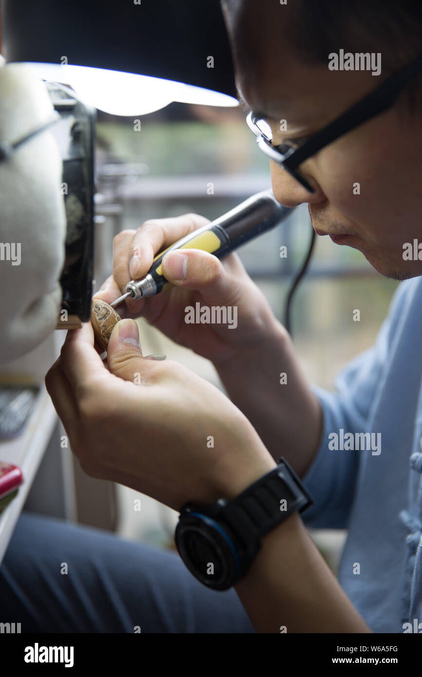 An apprentice creates a fruit pit carving at a studio in Zhoushan ...