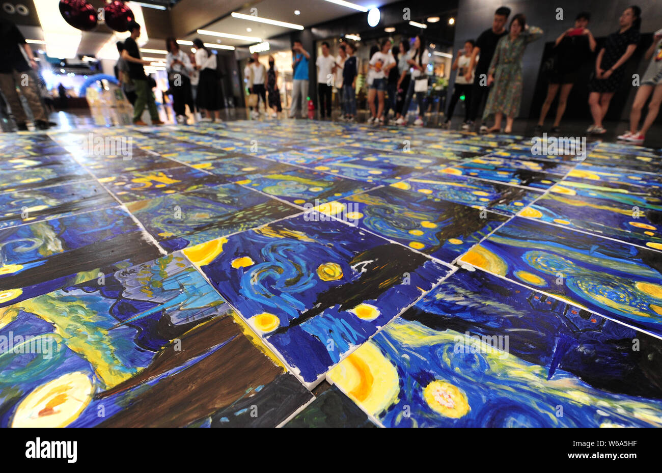 Visitors look at a large painting made of different versions of Vincent ...