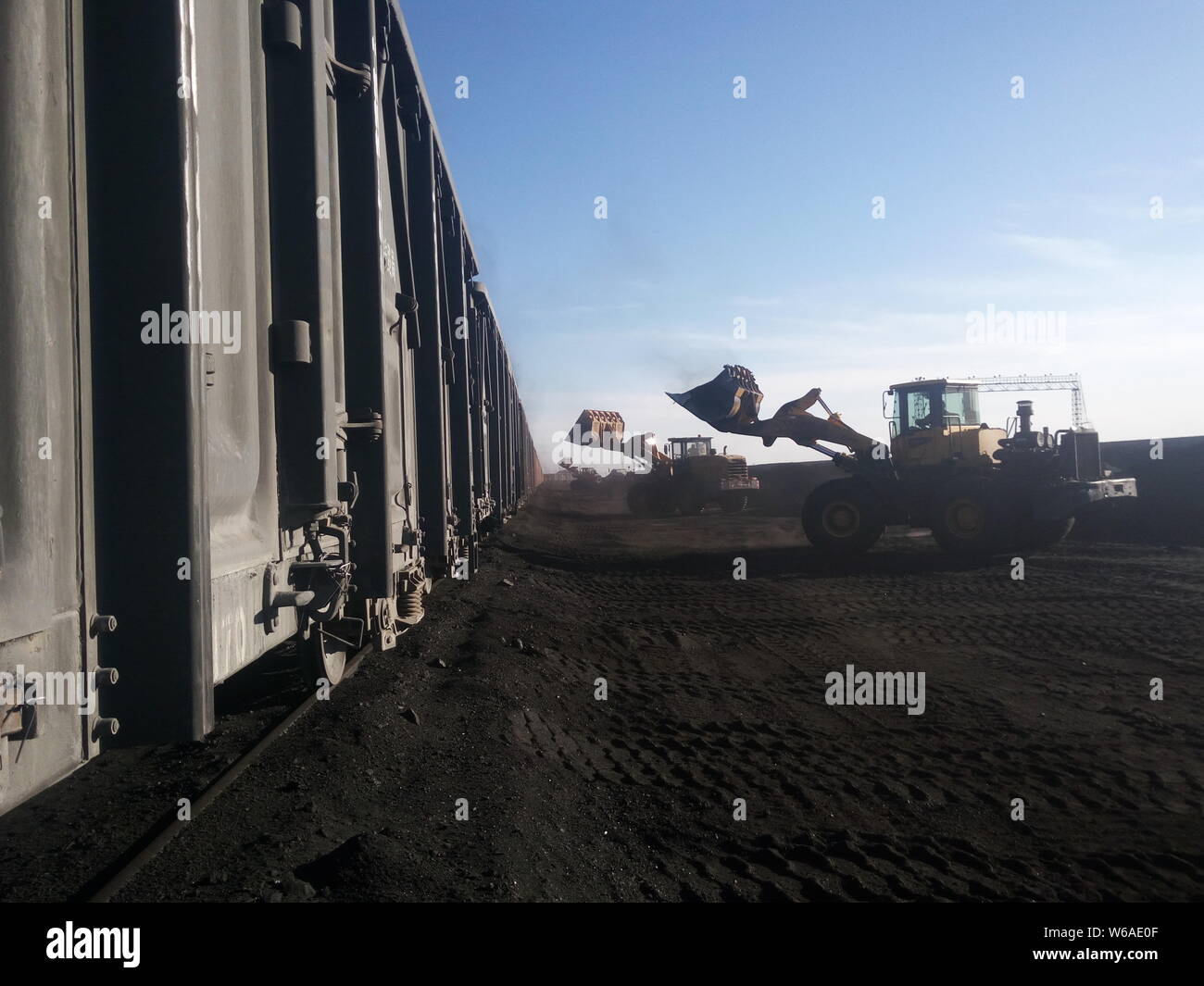 --FILE--Chinese workers drive wheel loaders to load a freight train ...