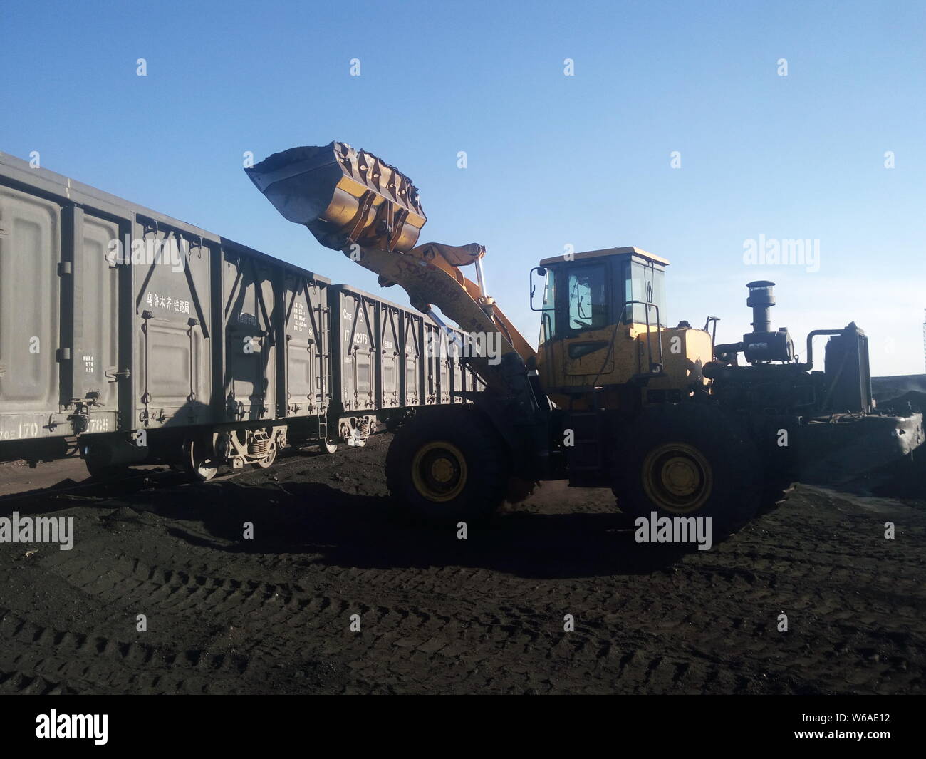--FILE--Chinese workers drive wheel loaders to load a freight train ...
