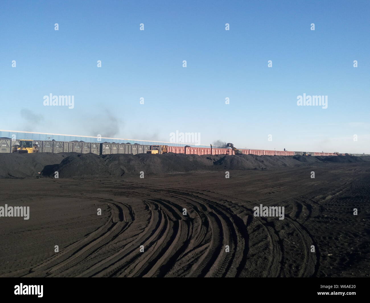 --FILE--Chinese workers drive wheel loaders to load a freight train ...