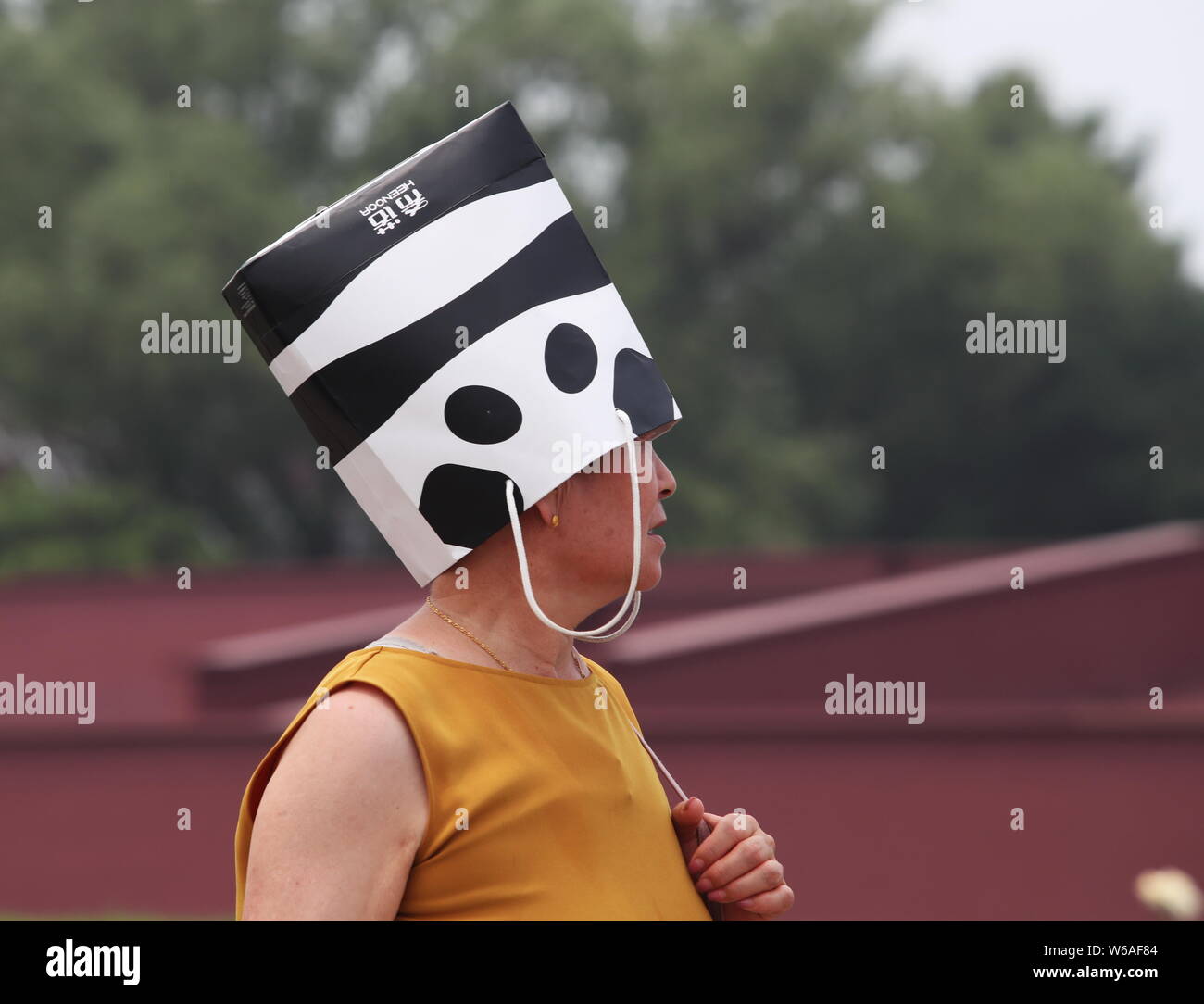 A tourist wears a paper bag to shield herself from the scorching sun as ...