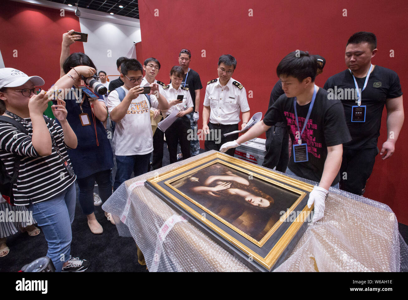 Chinese security guards show an artwork to be on display during an art ...