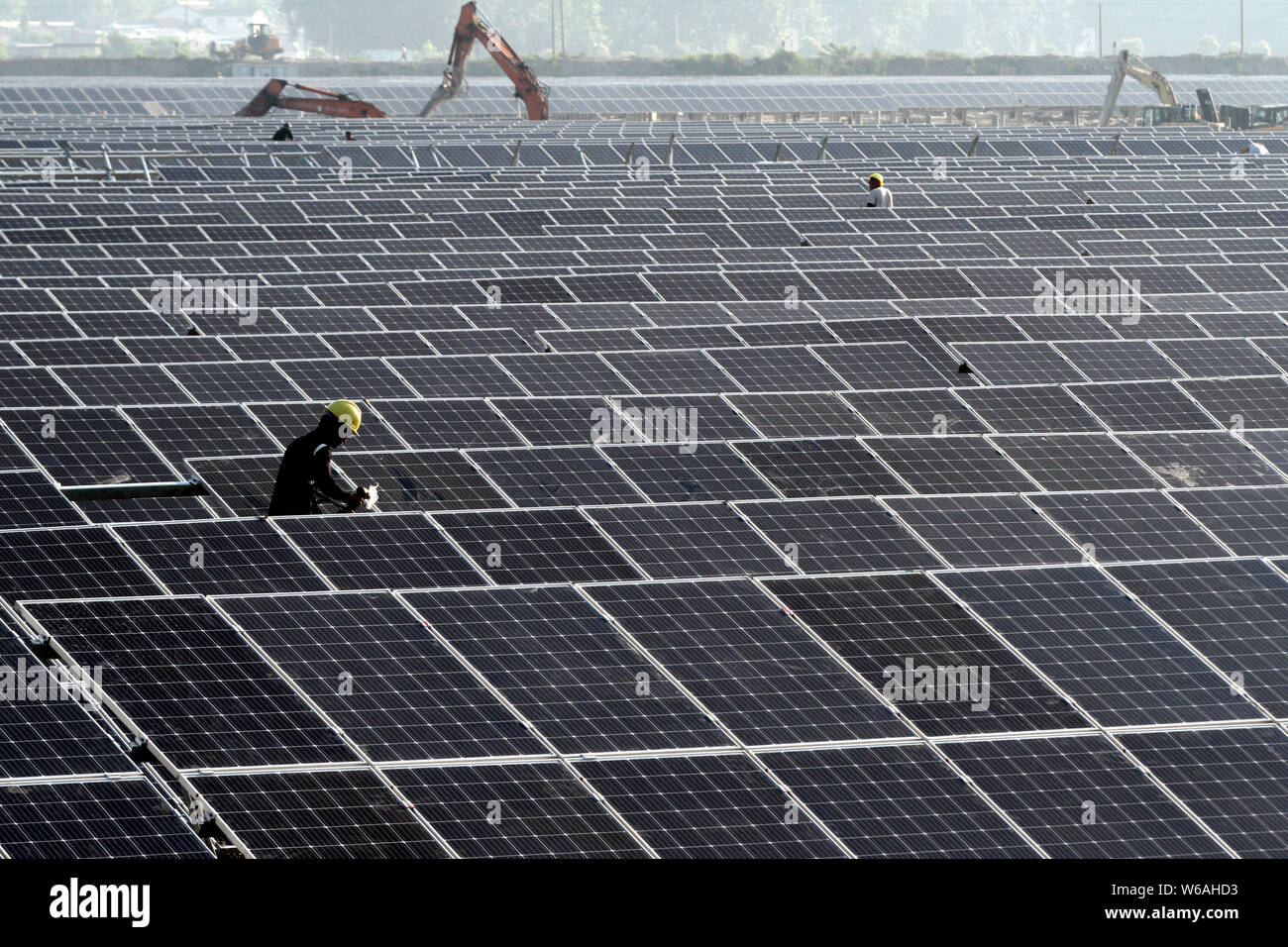 Chinese workers install solar panels at a photovoltaic power station in ...