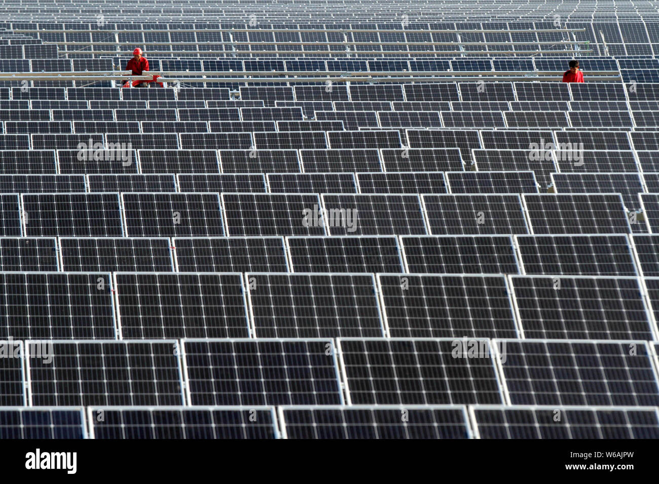 Chinese workers install solar panels at a photovoltaic power station in ...