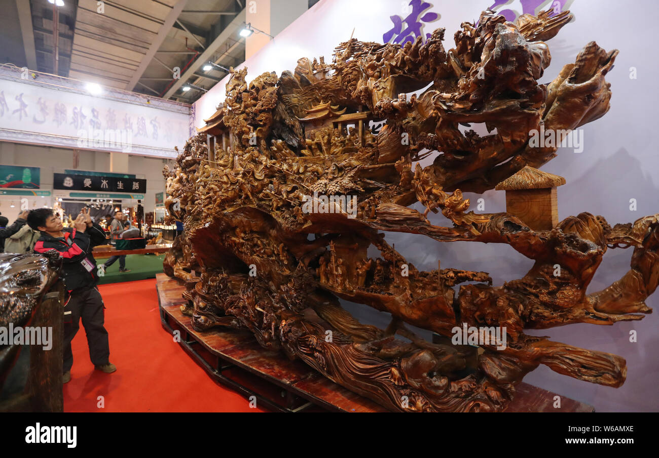 A visitor takes photos of a wooden sculpture featuring 108 heroes ...