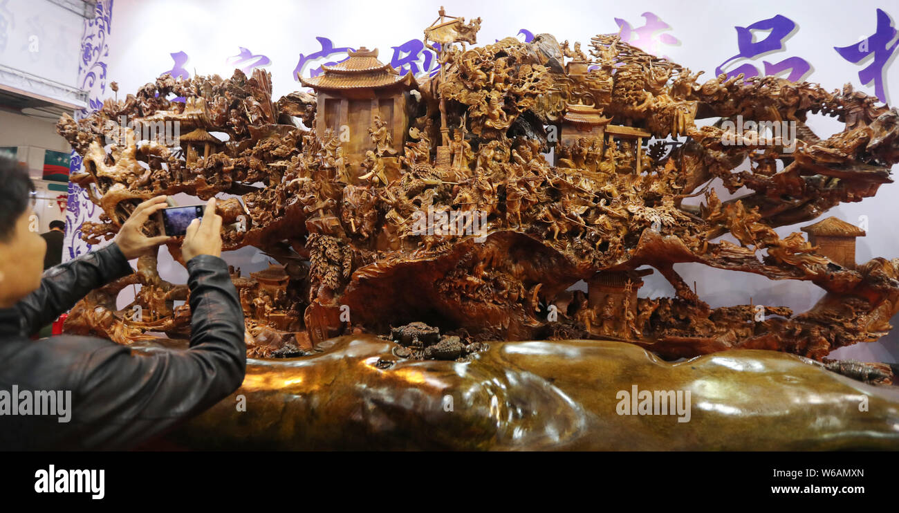 A visitor takes photos of a wooden sculpture featuring 108 heroes ...