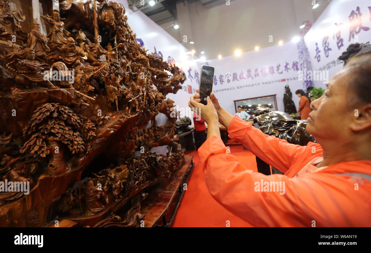 A visitor takes photos of a wooden sculpture featuring 108 heroes ...