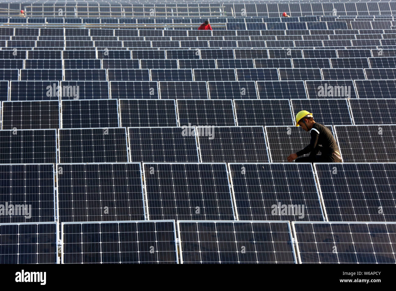 Chinese workers install solar panels at a photovoltaic power station in ...