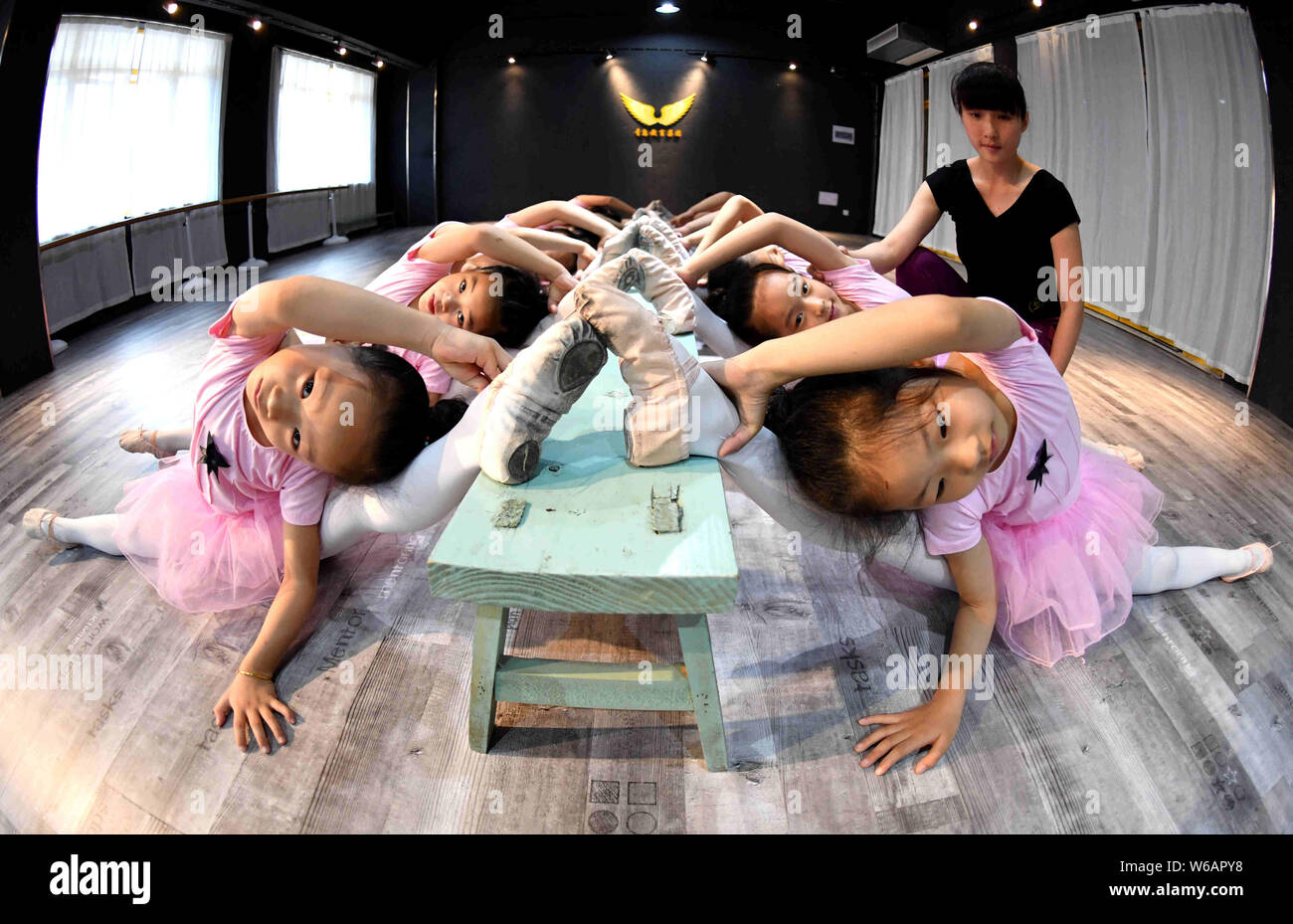 A Chinese Teacher Instructs Young Girls To Stretch Their Legs And Bend
