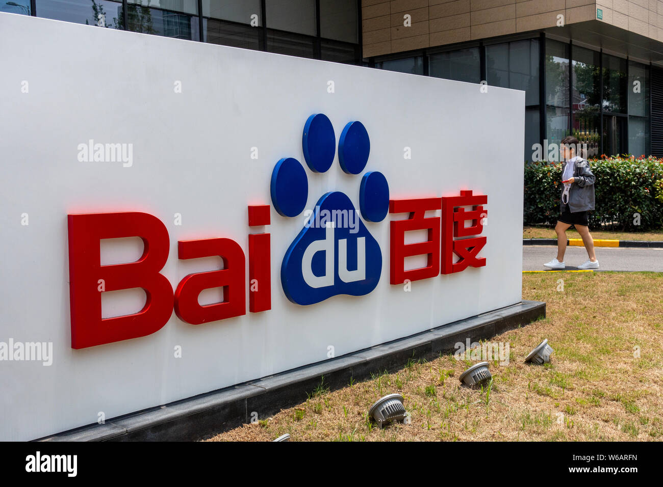 A pedestrian walks past a signboard of Baidu at an office building in ...