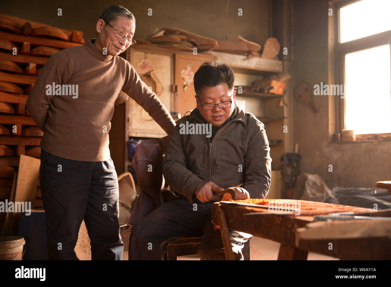 --FILE--Chinese craftsman Li Zhaolin instructs a visitor to make Pipa ...