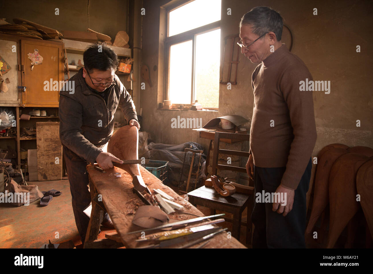 --FILE--Chinese craftsman Li Zhaolin instructs a visitor to make Pipa ...