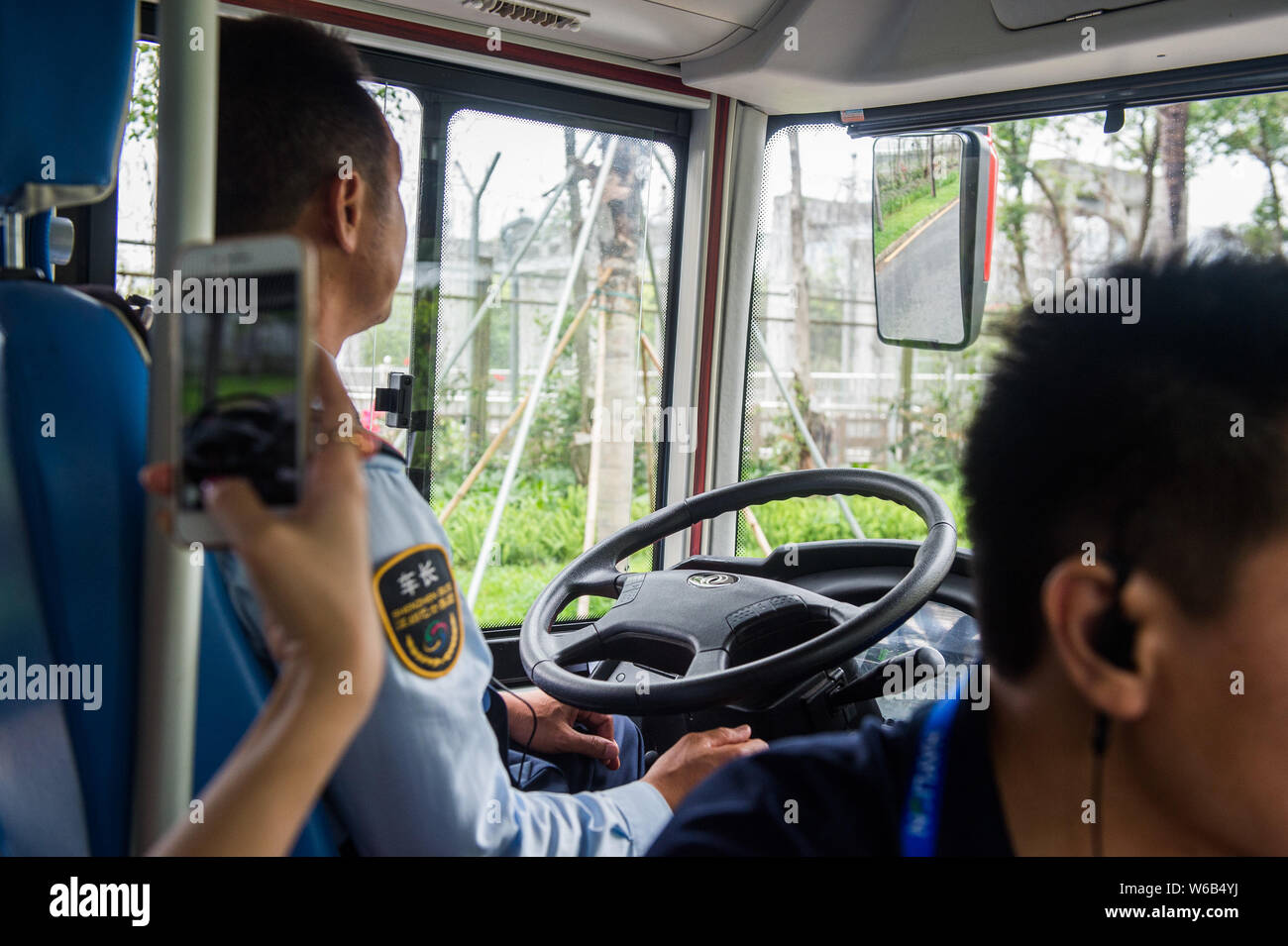 A driver sits in the driver's seat as an Alphabus smart bus with self ...