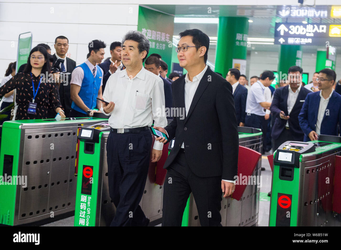 Pony Ma Huateng, right, Chairman and CEO of Tencent Holdings Ltd., uses his smartphone to have ...