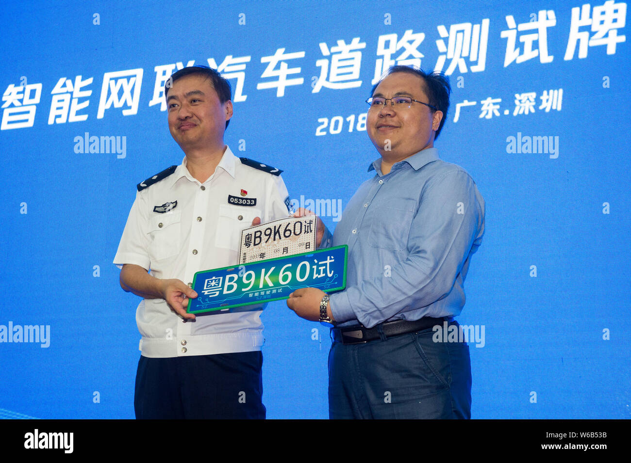 An officer of the Shenzhen Transport Bureau issues the license plate ...