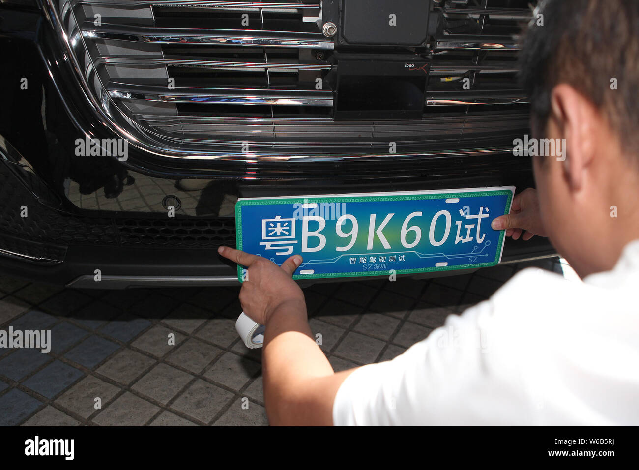 An employee installs the license plate for a self-driving car of ...