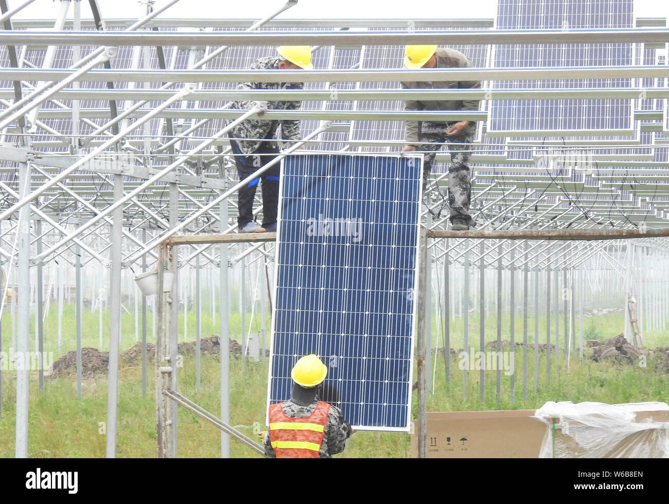 Chinese workers install solar panels at a photovoltaic power station in ...