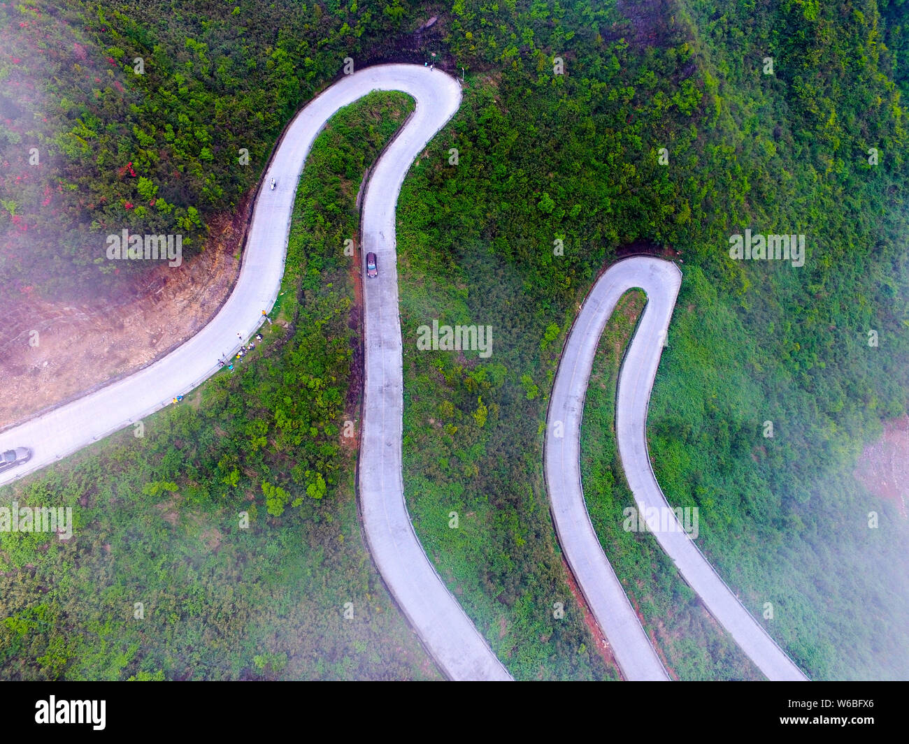 Cars drive on a section of winding road with 45 curves linking Xiushan ...