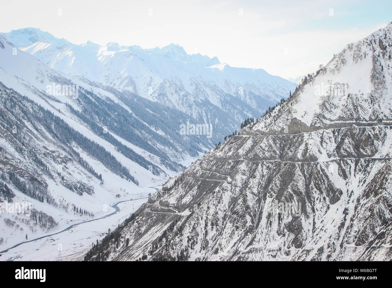 Distant view of a winding road on a snow covered mountain. Drone shot ...