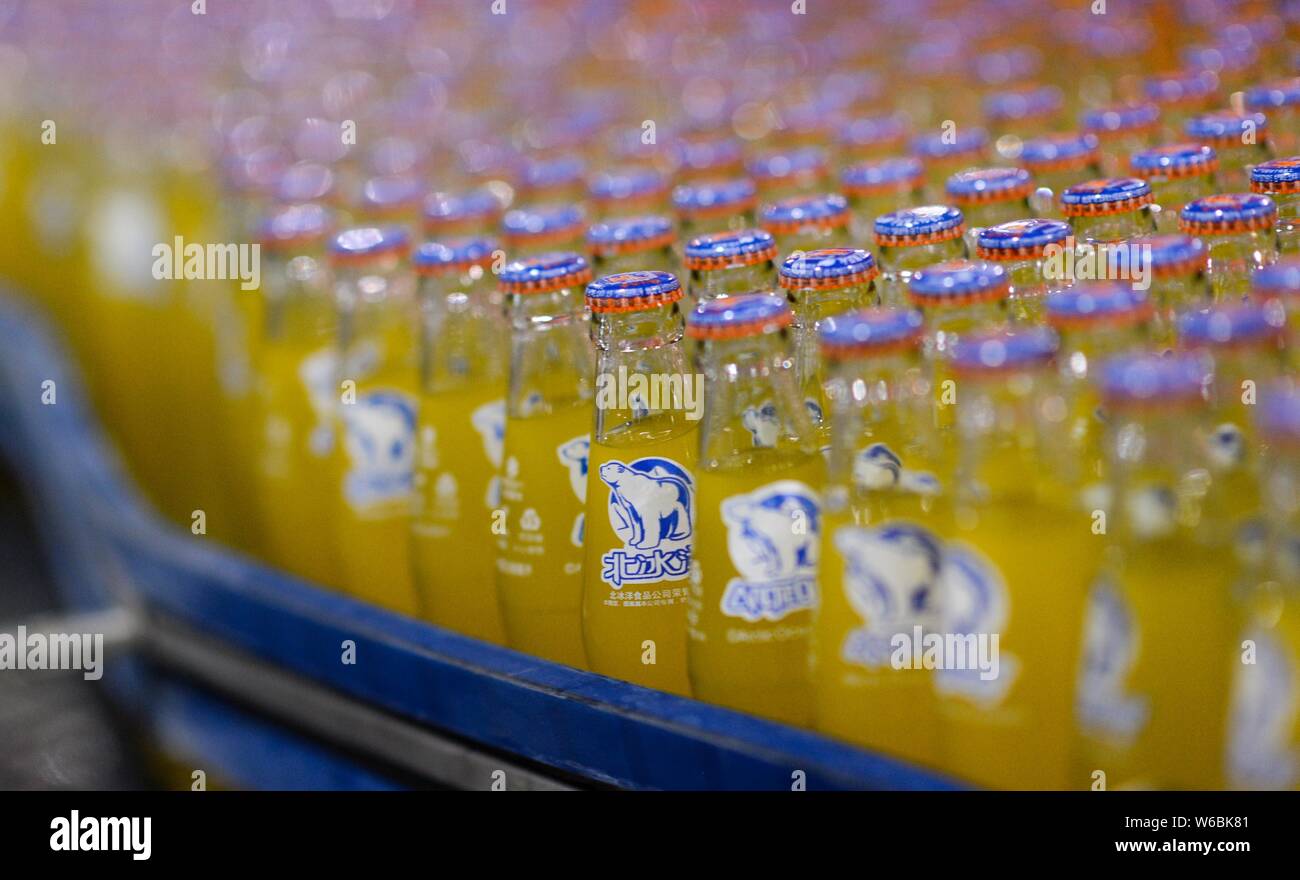 Bottles of orange soda are being produced on the assembly line at the ...