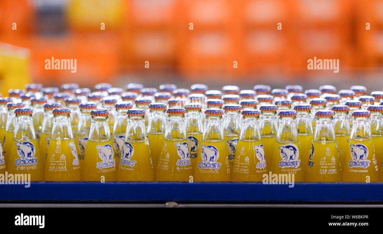 Bottles of orange soda are being produced on the assembly line at the ...