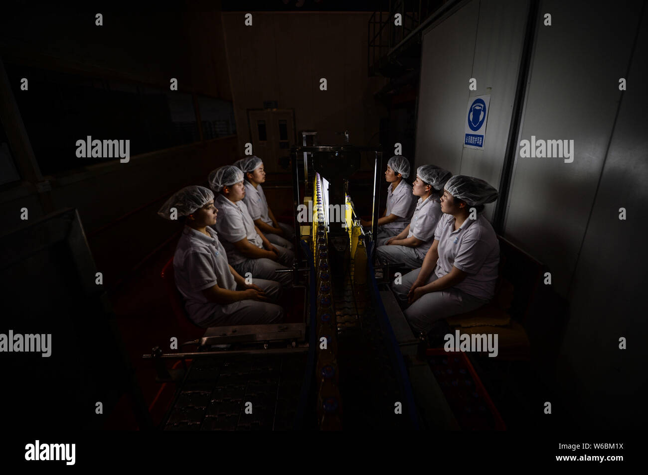 Chinese workers check the production of bottles of orange soda on the ...